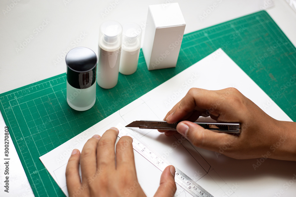 Hand holding cutter knife with ruler for cut plan box paper with empty ...