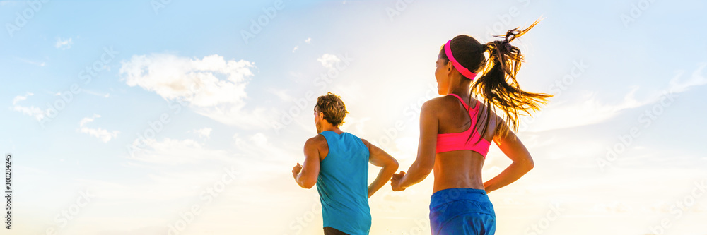 Runners fitness couple running together on sunset sky background ...