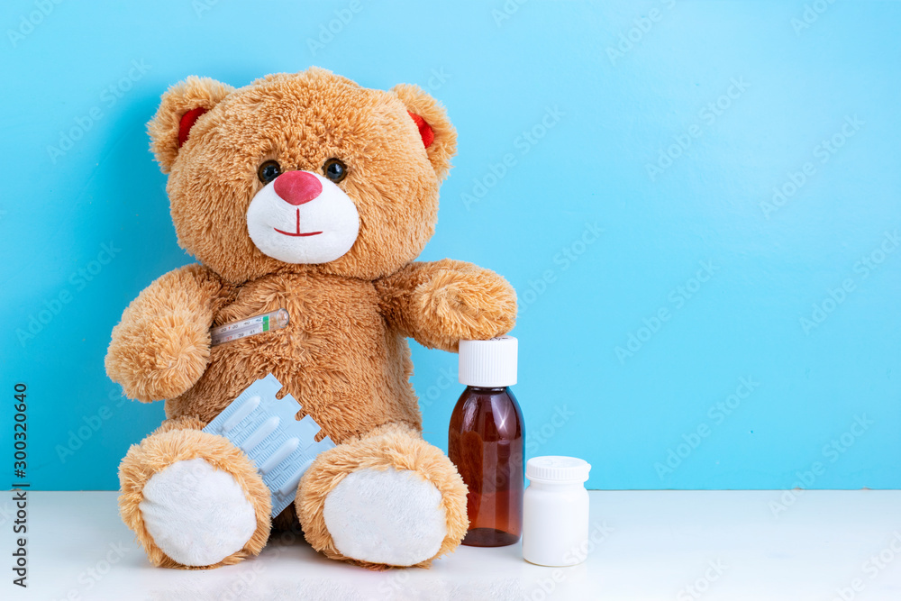 Teddy bear, thermometer, antipyretic candles, pills and cough syrup on ...