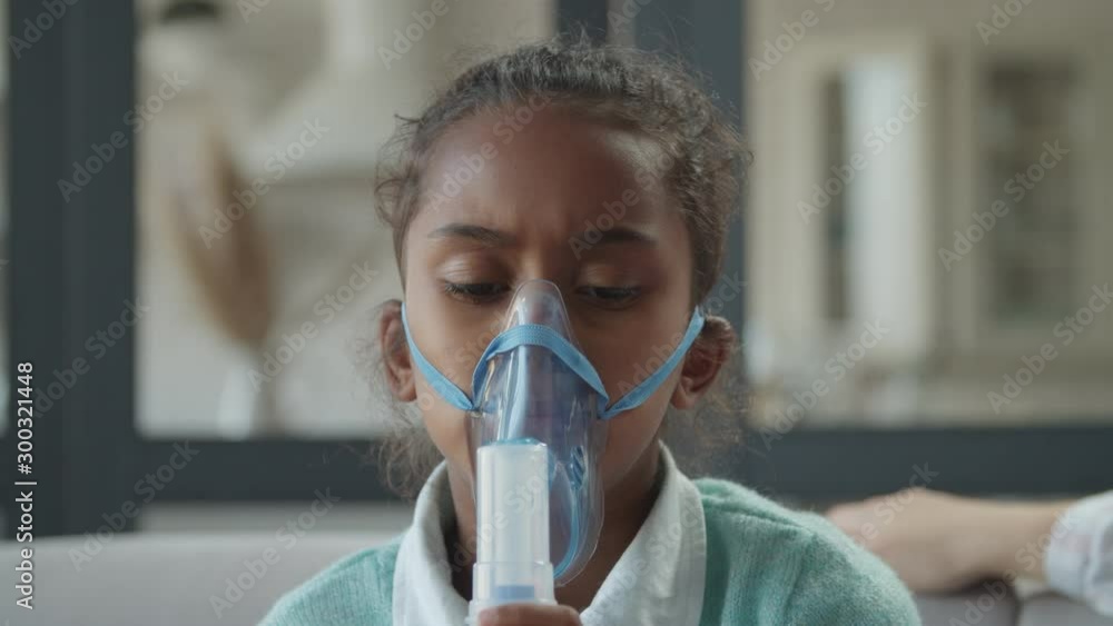 Portrait of beautiful african american elementary age girl doing asthma ...