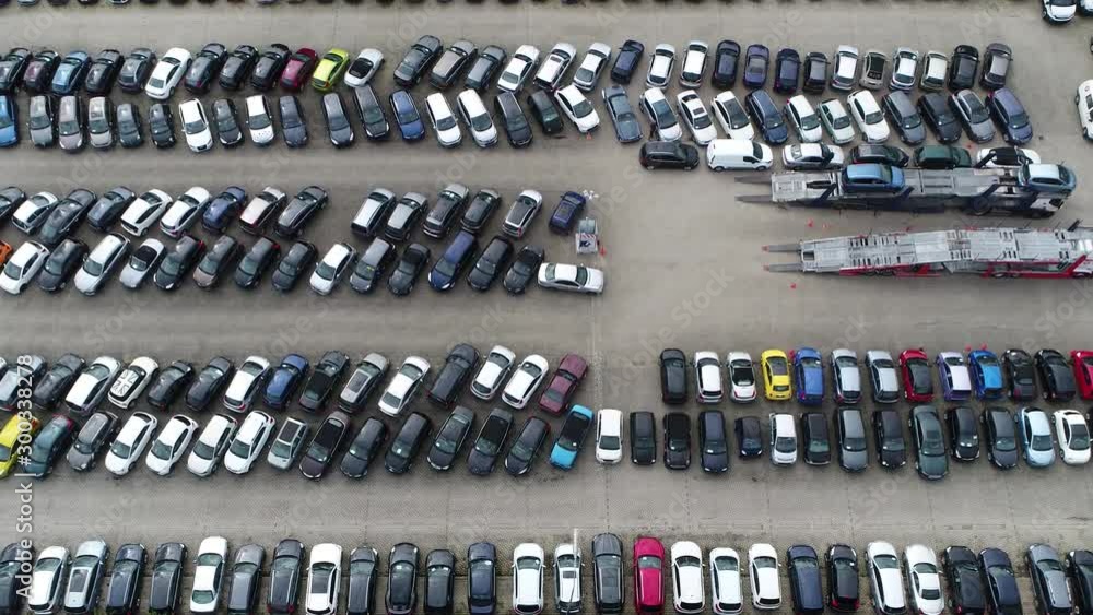 Aerial birds eye view moving towards used car dealership lot showing ...