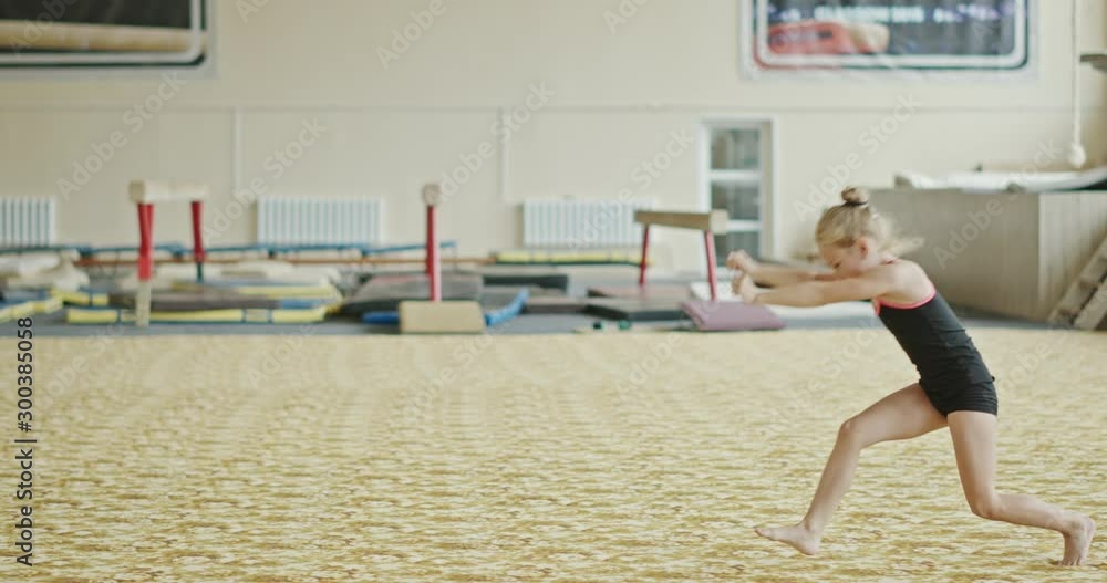 Agile young girl practising in a ballet studio turning an elegant cart ...