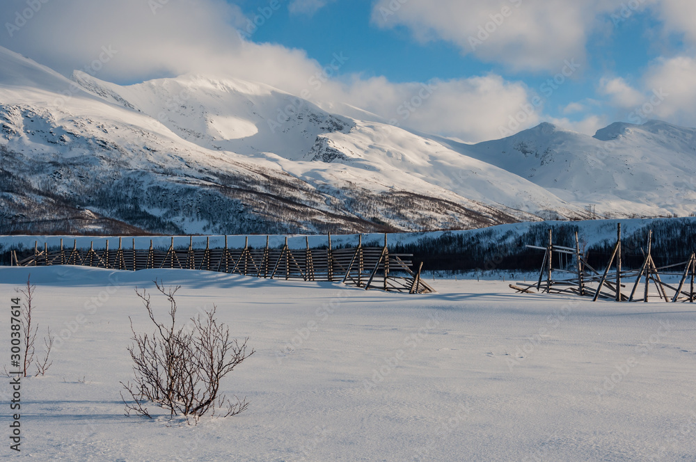 Partly broken snow fence with mountains in the background in northern ...