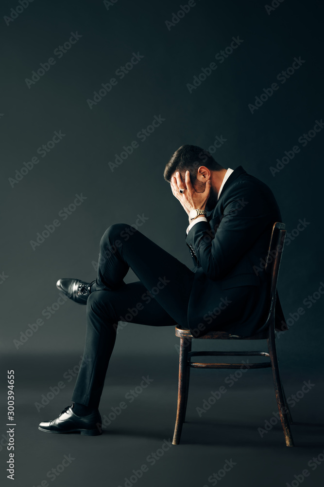 Sad unhappy man in black suit sitting on the chair and closed face by ...