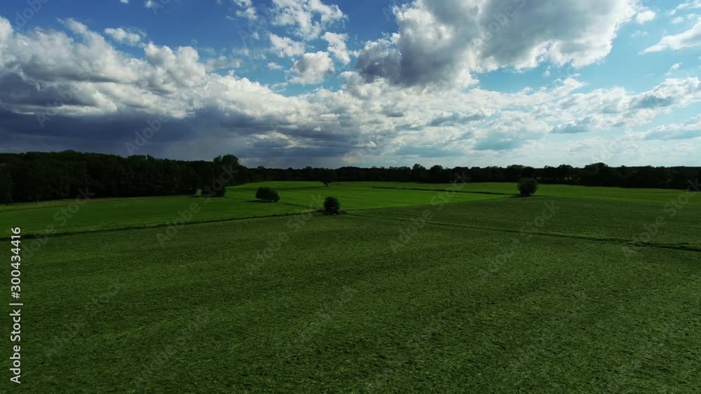 Aerial top-down view of green grass farm field with tractor raking ...