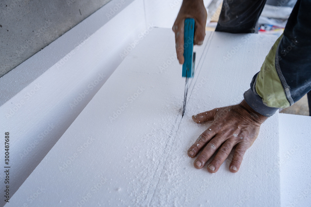Construction worker using the hand saw to cut the styrofoam insulation ...