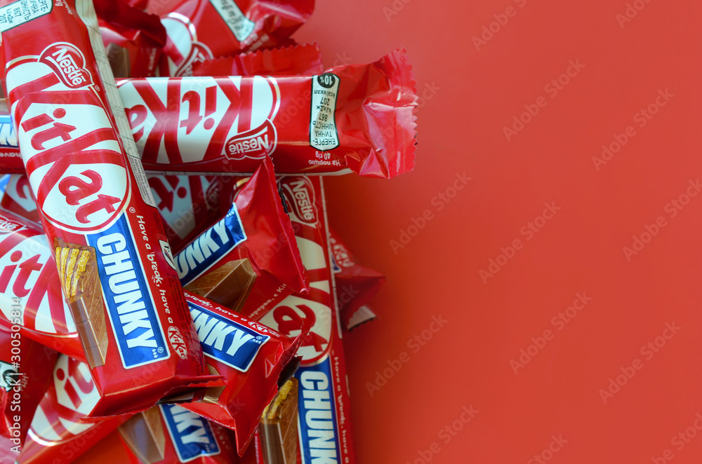 Kit Kat chocolate bars in red wrapping lies on yellow background is now ...