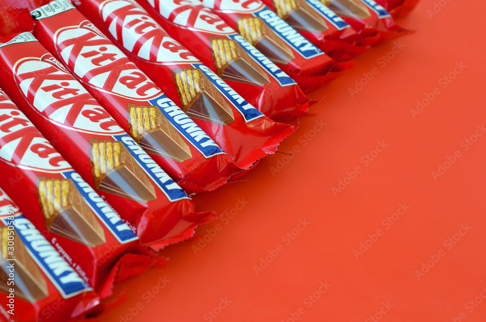 Kit Kat chocolate bars in red wrapping lies on yellow background is now ...