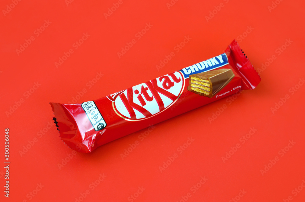 Kit Kat chocolate bar in red wrapping lies on bright red background ...
