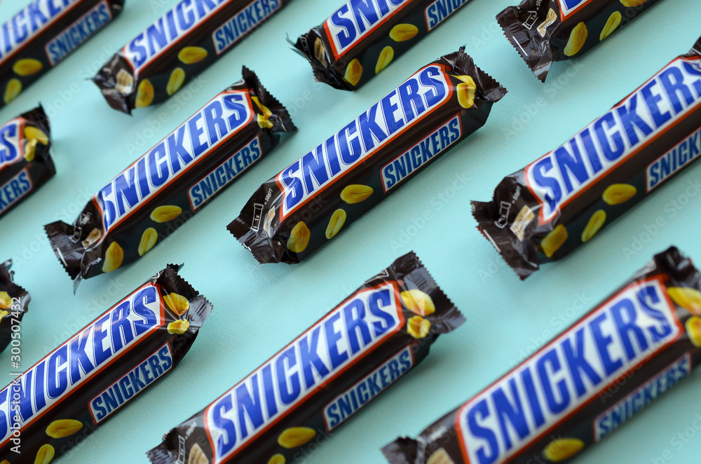 Many Snickers chocolate bars lies on pastel blue paper. Snickers bars ...