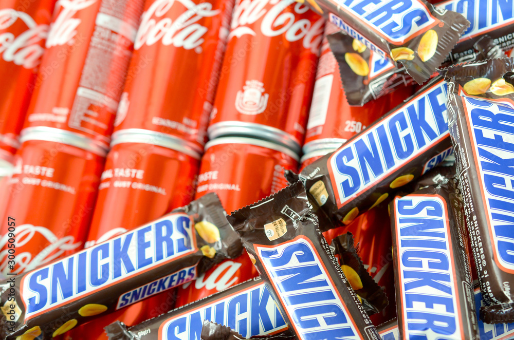 Snickers chocolate bars in brown wrapping lies on red Coca Cola tin ...