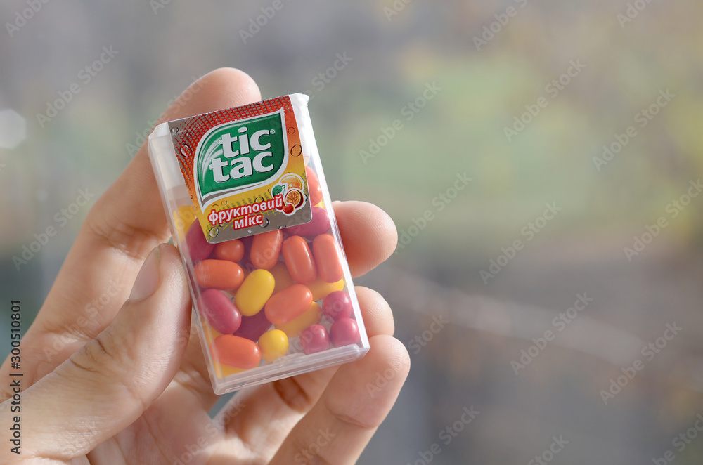 Hand holds Fruit mix Tic Tac Candy package close up. Tic tac is popular ...