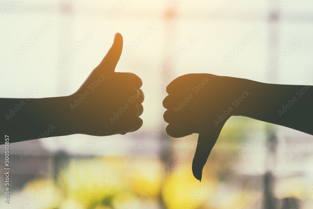 Silhouette image of two hands making thumbs up and thumbs down sign ...