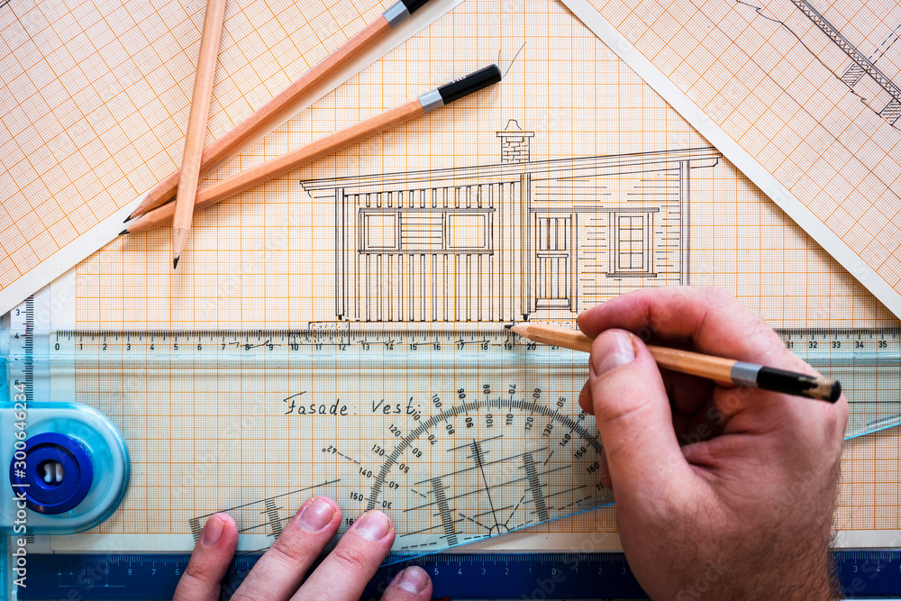 Hands drawing cabin on drawing board with ruler and pencils. Designer ...