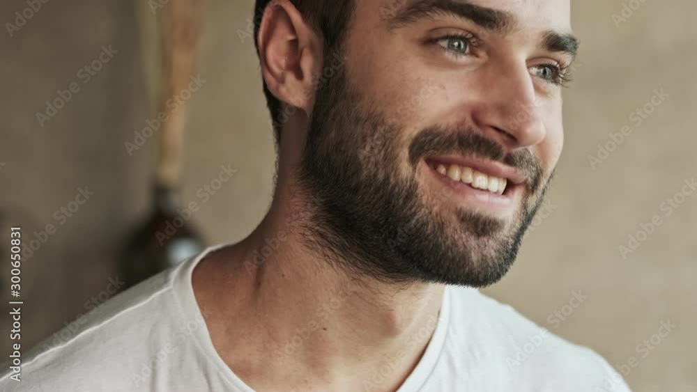 Close up view of handsome happy young brunet man smiling while looking ...