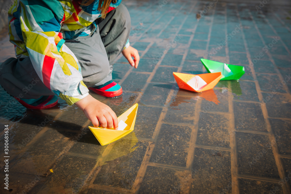 child playing with paper boats in water puddle Stock Photo | Adobe Stock