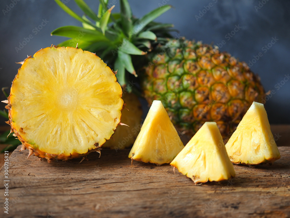 Ripe pineapple fruit cut in half and triangle shape on a rustic wooden ...