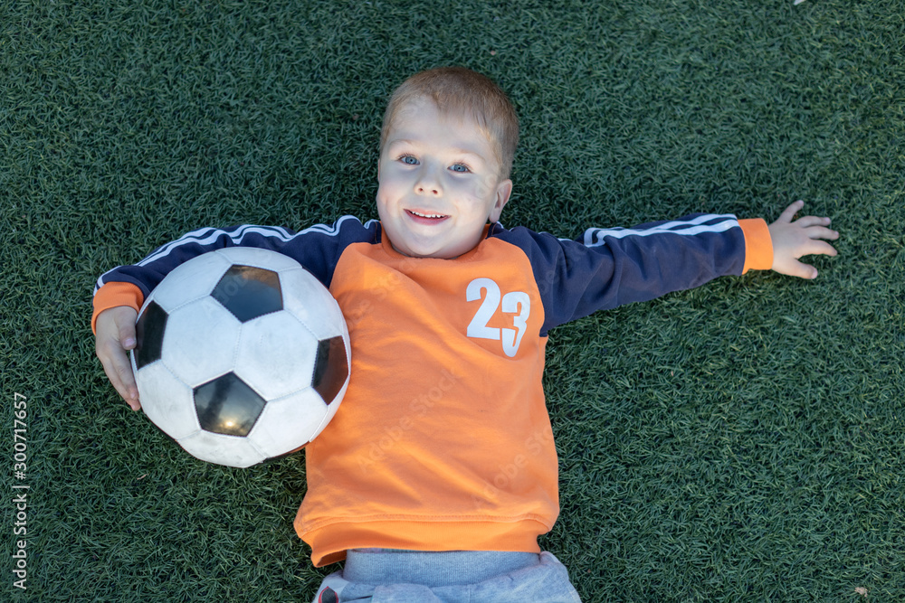 boy playting football on the field with gates. Active child in summer ...