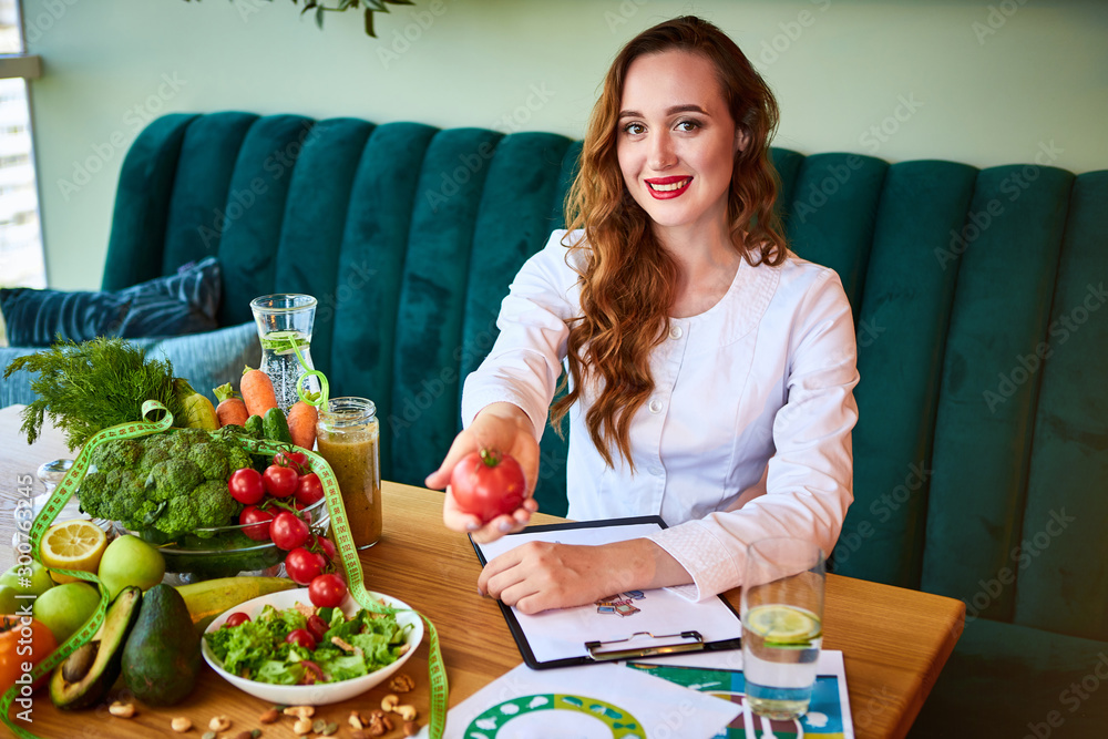 Woman dietitian in medical uniform with tape measure working on a diet ...