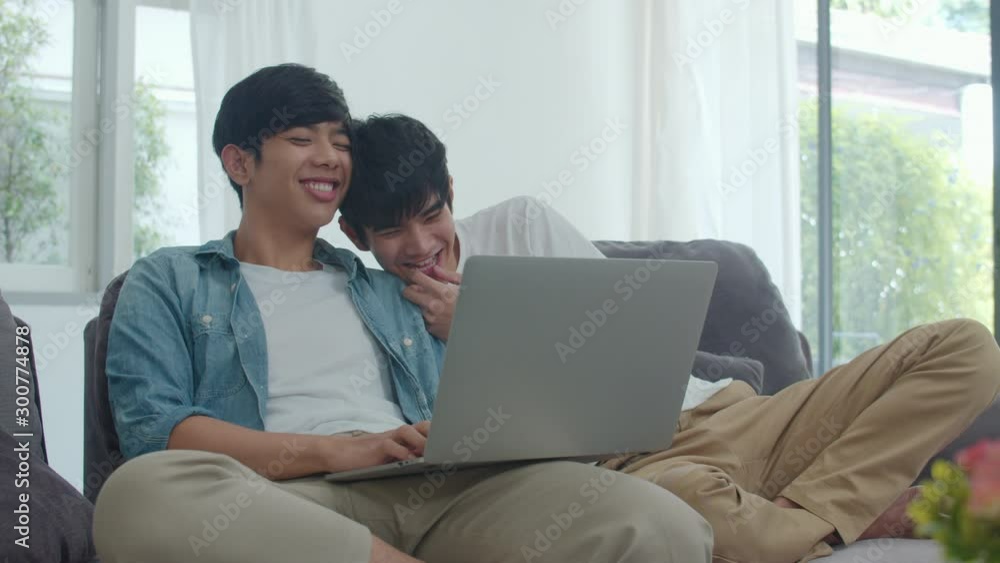 Young Gay couple using computer laptop at modern home. Asian LGBTQ men ...