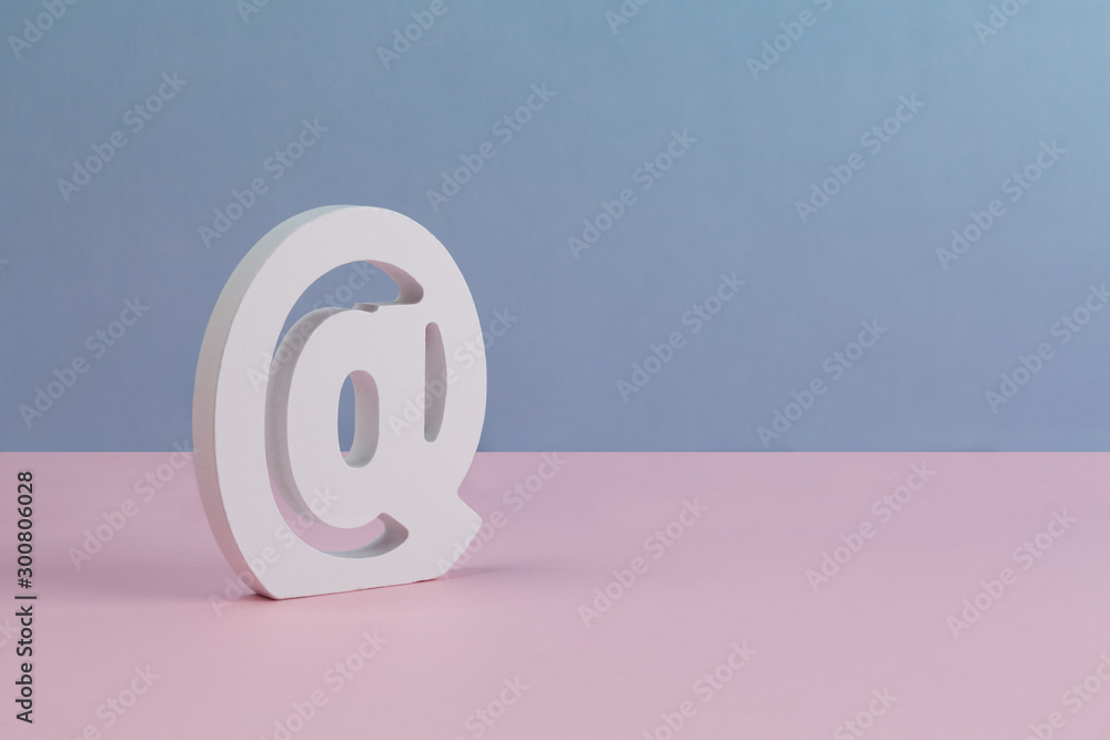 Carved Email symbol at placed on clean pink blue background with copy ...