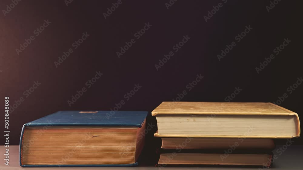 Stop motion stacking old books on a black background. growing book pile ...