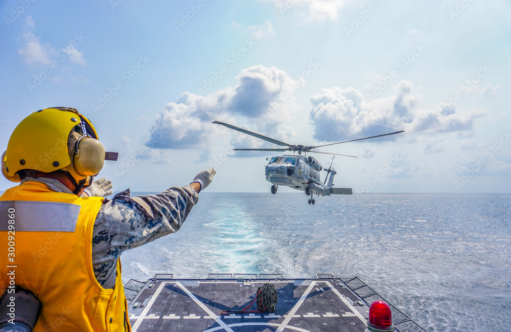 signal man give signal hand to a military navy helicopter above ...