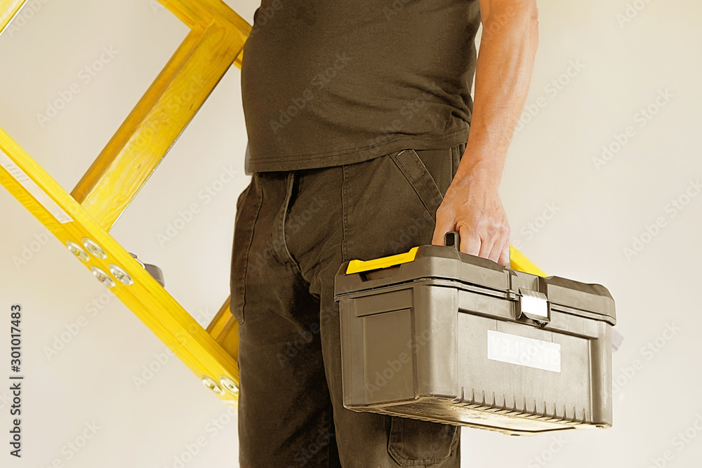 Electrician holds tool box and yellow wooden ladder. The builder ...