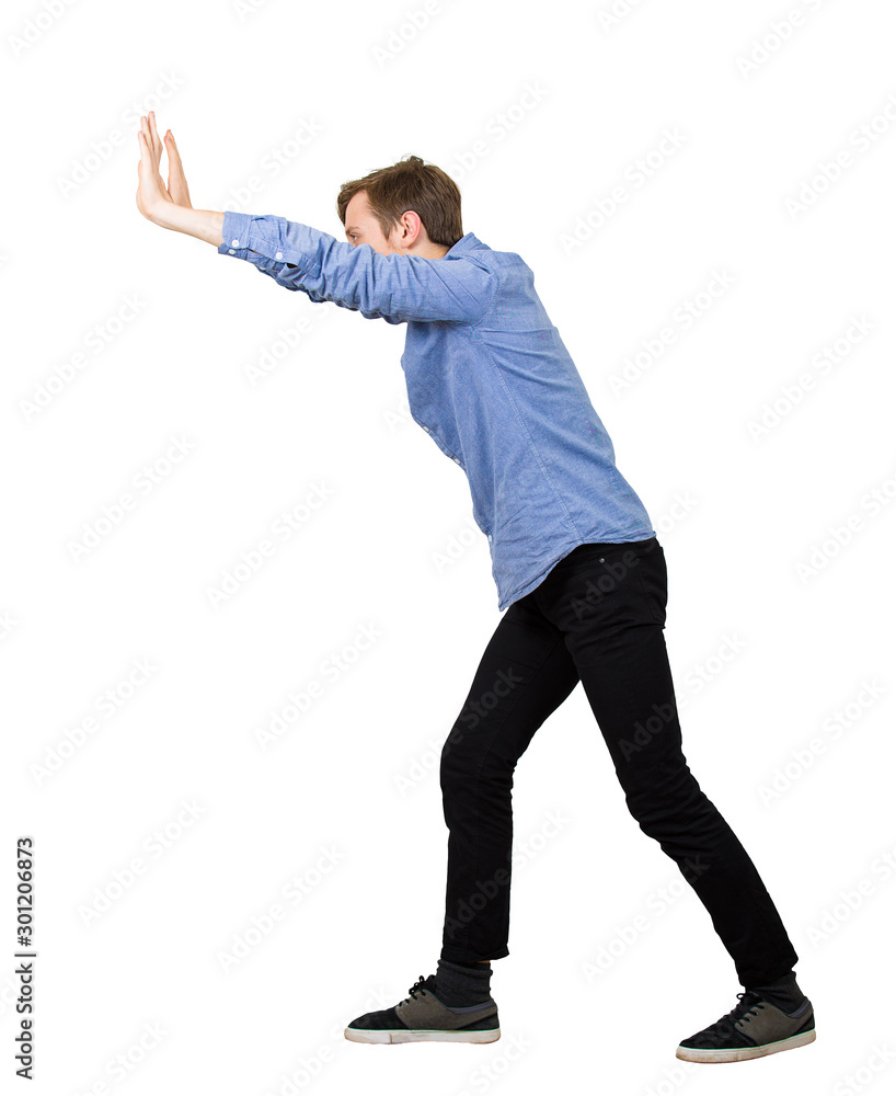 Determined teenage guy making effort as pushing an heavy invisible ...