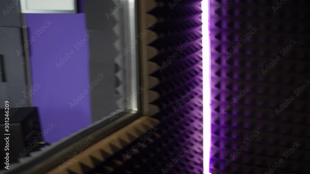 Young pop singer in headphones singing in microphone in booth in sound ...