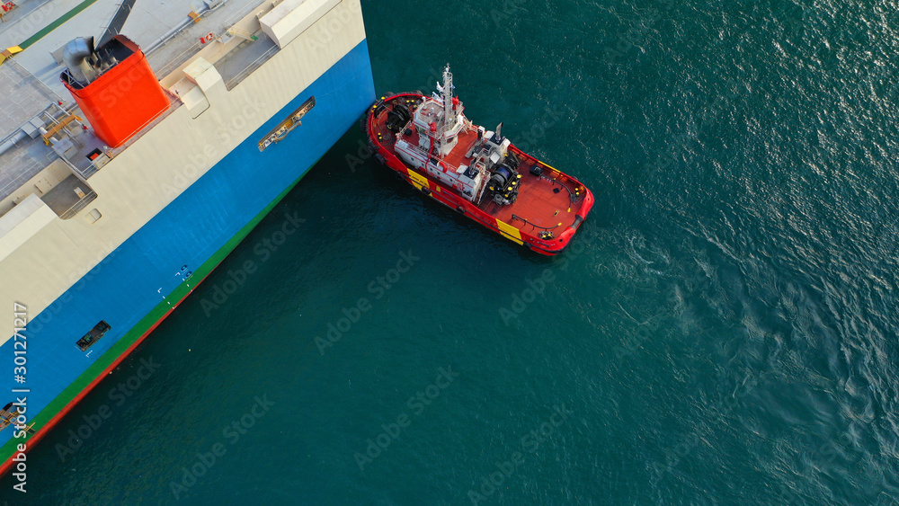 Aerial top down view of tug boat assist vessel pushing large tanker to ...