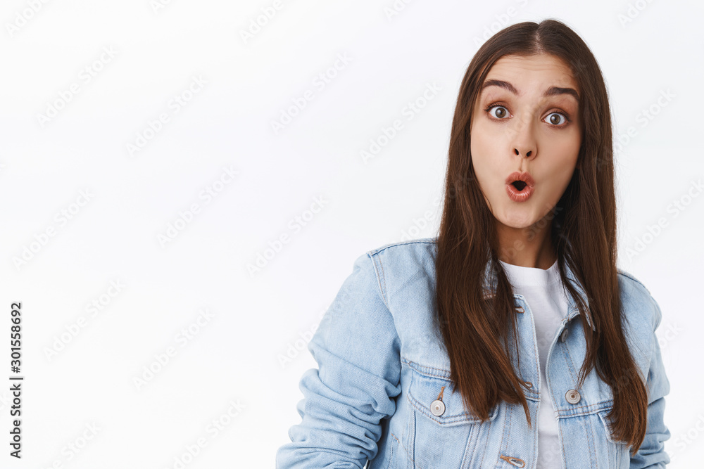 Surprised astonished brunette woman in denim jacket, folding lips ...
