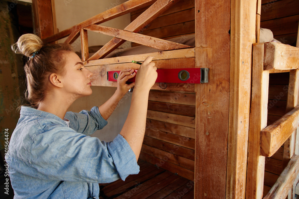 Beautiful young woman doing home renovation, observing wall alignment ...