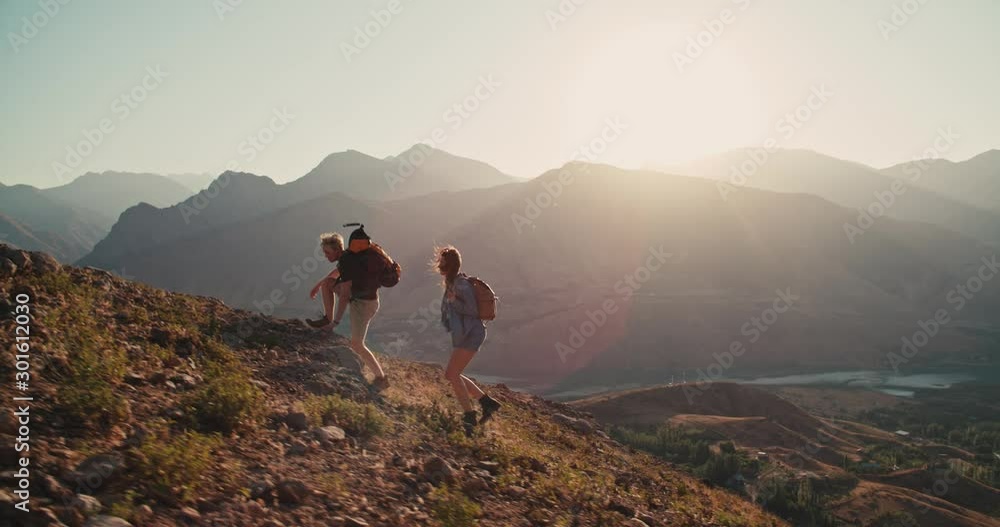 Caucasian couple hiking together with backpacks, helping each other on ...