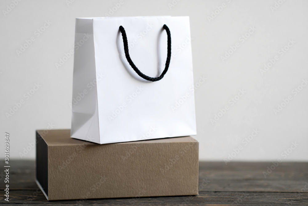 White paper bag and craft gift box on wooden table. Brand packaging ...