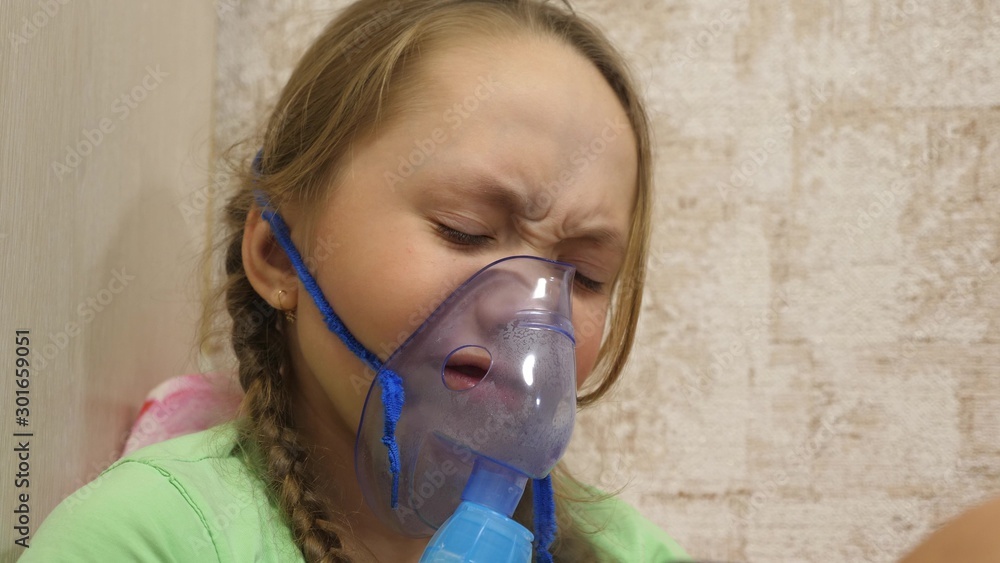 child with a tablet is sick and breathes through an inhaler. close-up ...