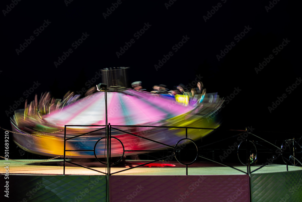 Amusement park ride fast spinning carousel roundabout with motion blur ...