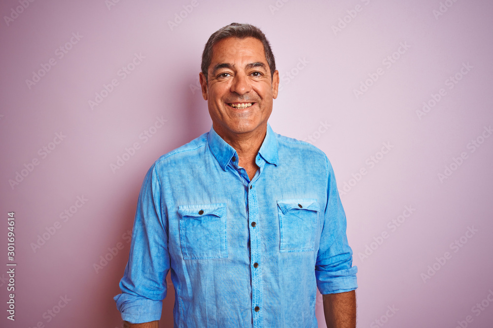 Handsome middle age man wearing blue denim shirt standing over isolated ...