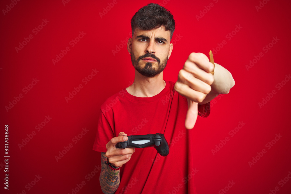 Young gamer man with tattoo playing video game standing over isolated ...