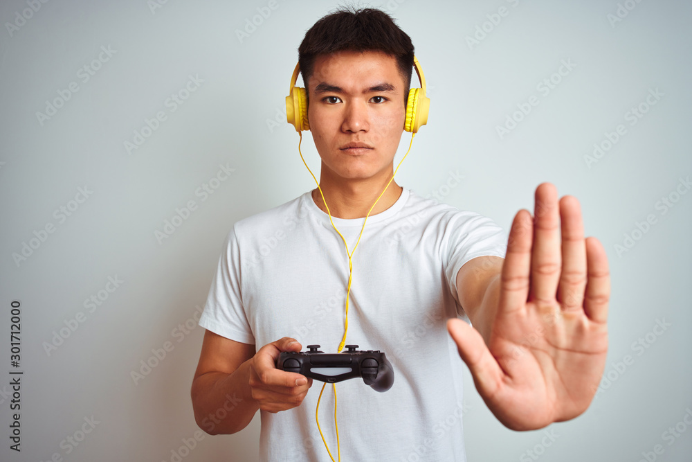 Young asian chinese gamer man playing video game standing over isolated ...
