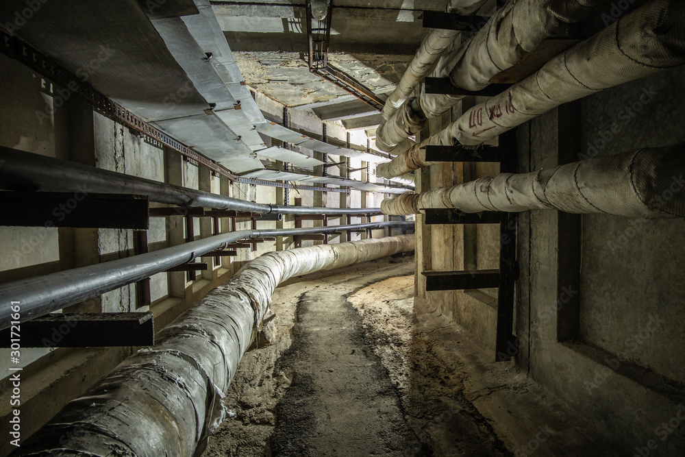 Underground concrete utility tunnel with pipes and wires. This tunnel ...