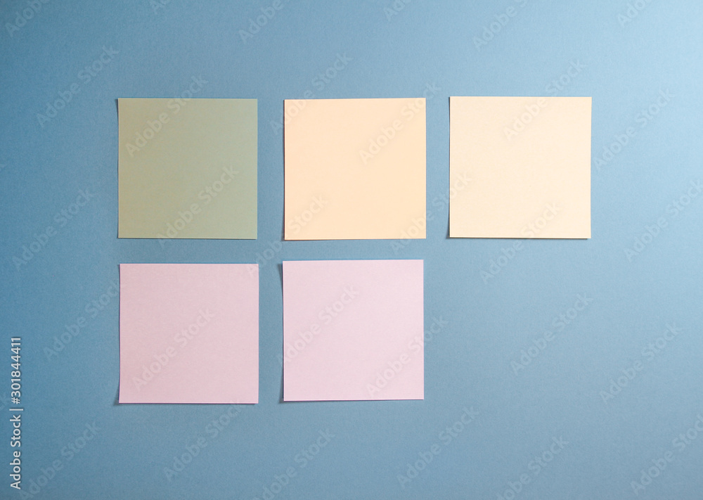 5 blank empty white and pastel colors sticky notes on clean blue ...