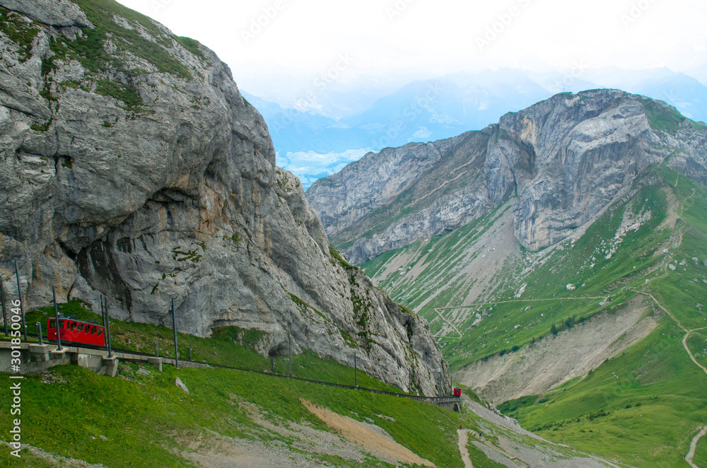 Red train in the distance moving on the railway in the mountains of ...