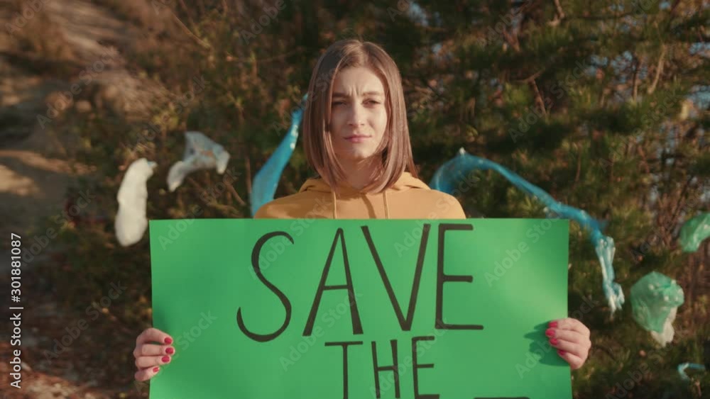 Serious young woman activist holding encouraging green poster Save the ...