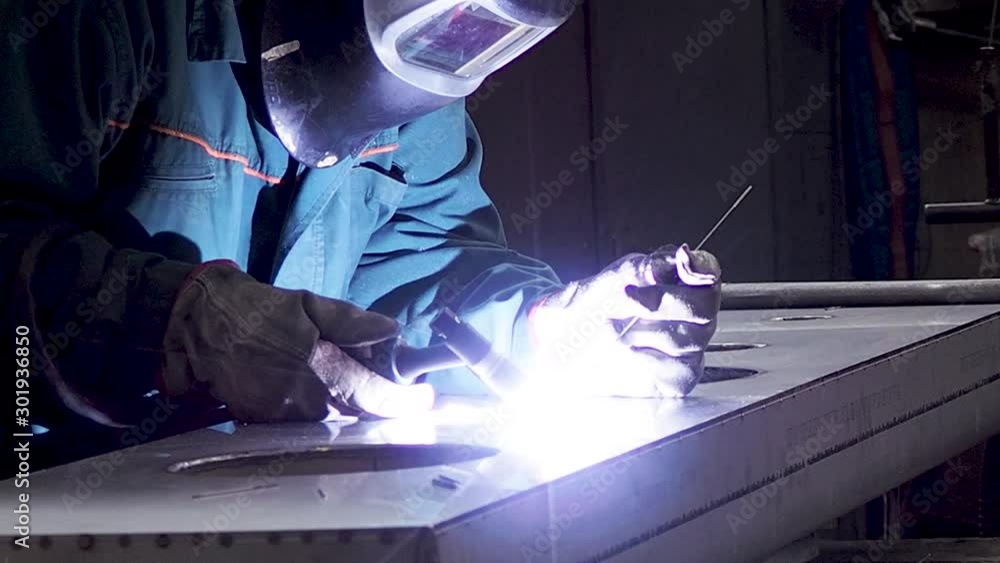 Static shot of worker welding stainless steel part, using TIG, MIG ...