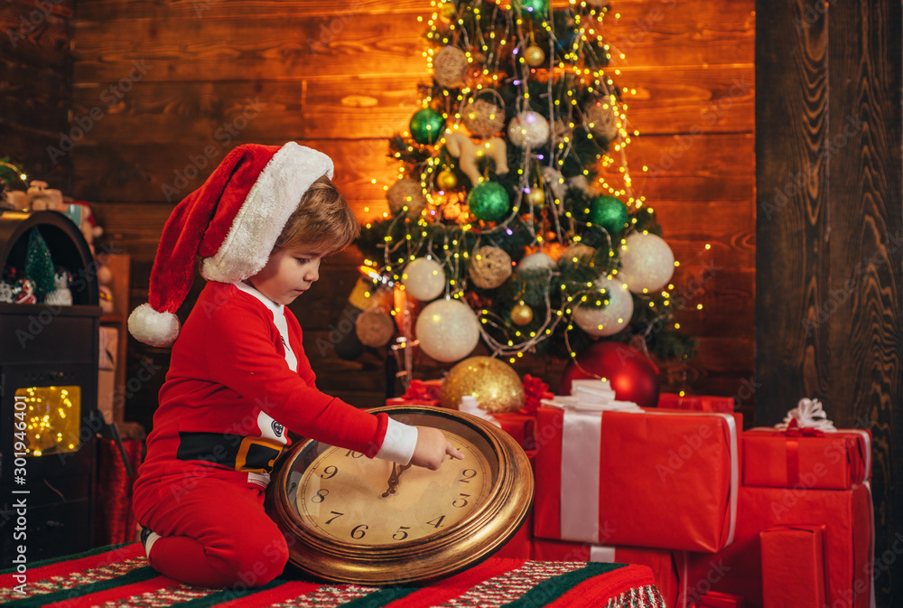 Little Santa kid waiting a New Year midnight and holding clock. Little ...