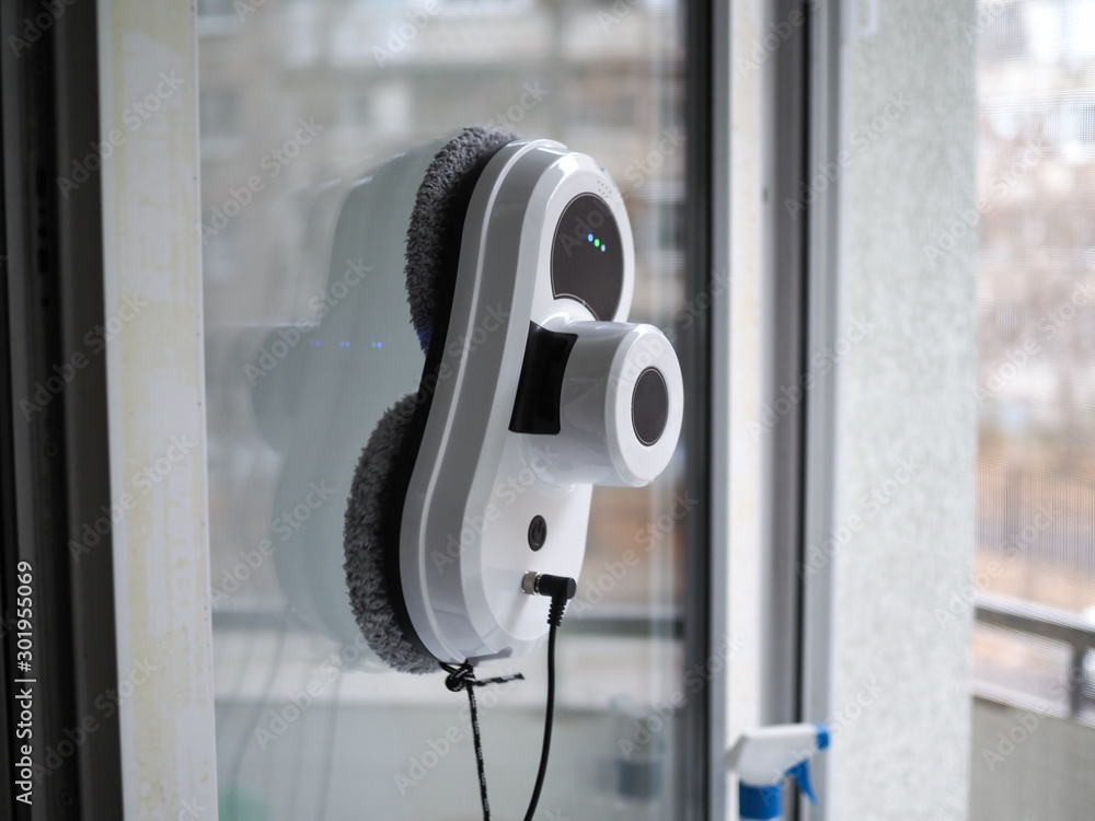 Domestic robot cleaning glass window on high rise building. Personal ...