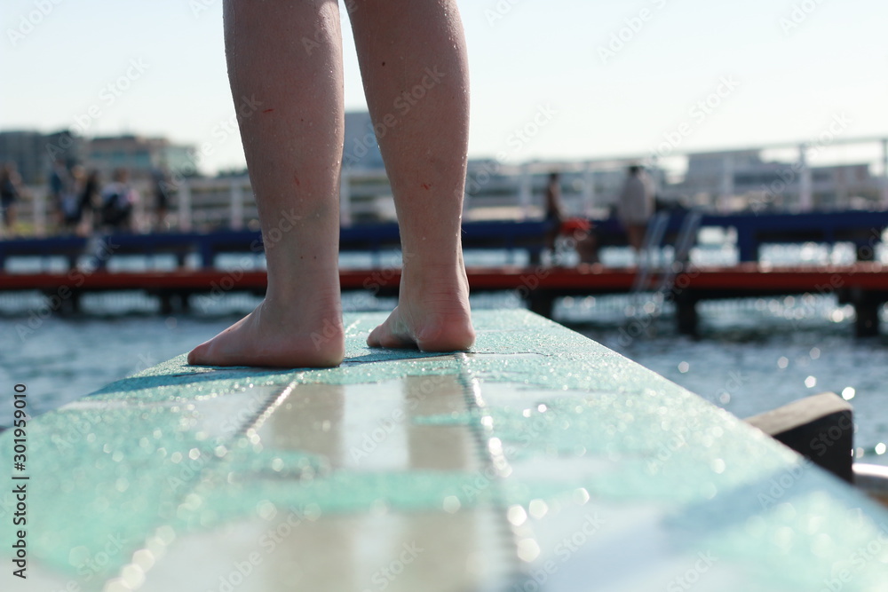 feet of a diver ready to dive off a blue diving board pocking out over ...