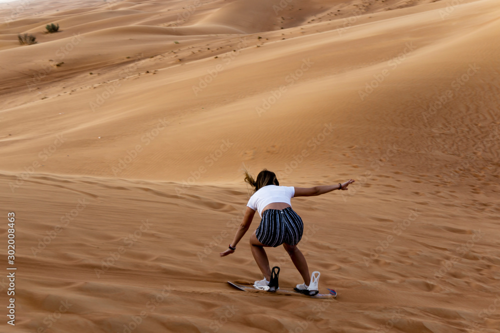 Young girl sandboarding in the desert - extreme desert activity Stock ...