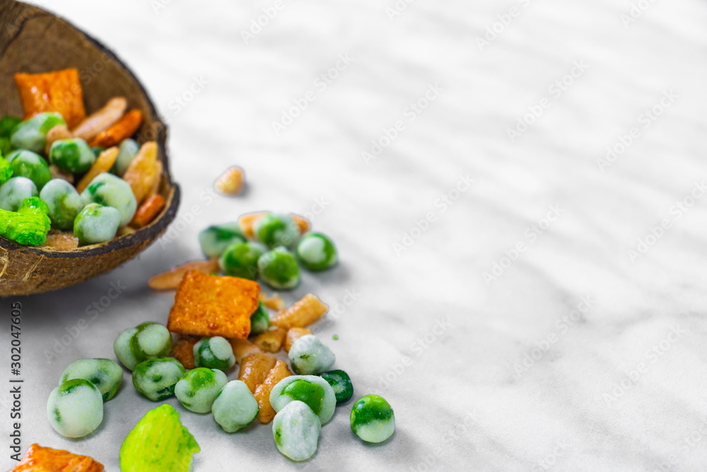 Japanese snacks with peas and wasabi lie in a coconut shell and on a ...